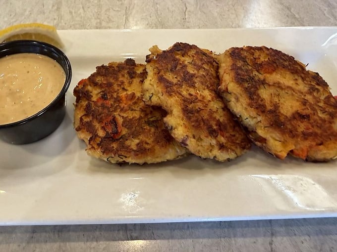Three golden crab cakes that look like they're auditioning for a seafood hall of fame induction ceremony.