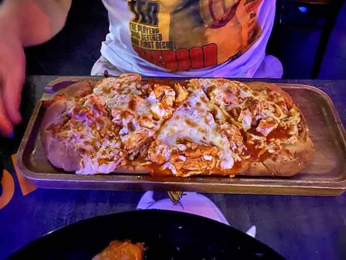 Buffalo chicken flatbread pizza stretches across the plate, loaded with toppings that make sharing an actual test of willpower.