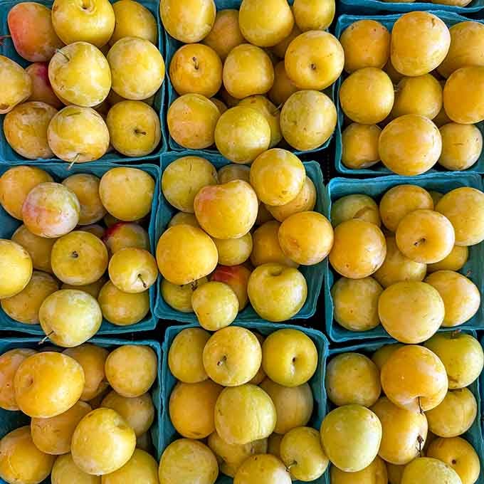 Golden plums packed in blue cartons glow like edible sunshine, ready to brighten your fruit bowl considerably.