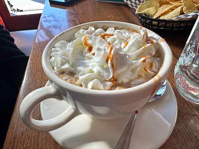 Hot chocolate topped with a mountain of whipped cream and caramel drizzle, because some mornings require extra comfort.