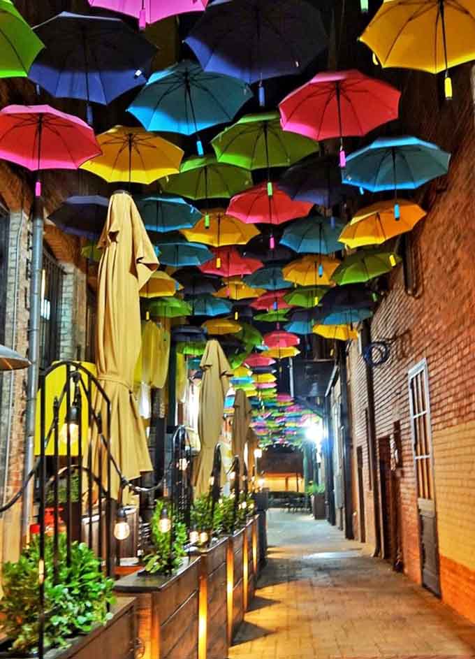 The alley transforms at night, with lights turning the umbrella canopy into a glowing dreamscape above.