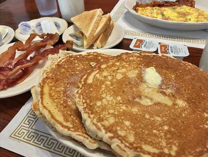 Pancakes the size of dinner plates, served with bacon because breakfast should always come with backup reinforcements.