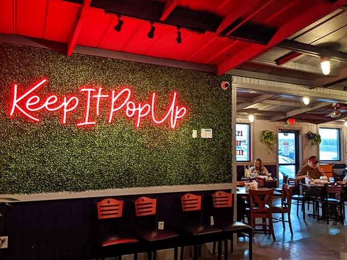 Red neon script spelling "Keep It Pop-Up" against greenery creates Instagram gold while diners enjoy their crispy treasures below.