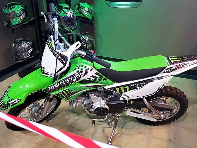 The Kawasaki dirt bike display proves this place celebrates all things motorsports, even the muddy outdoor kind you're avoiding today.