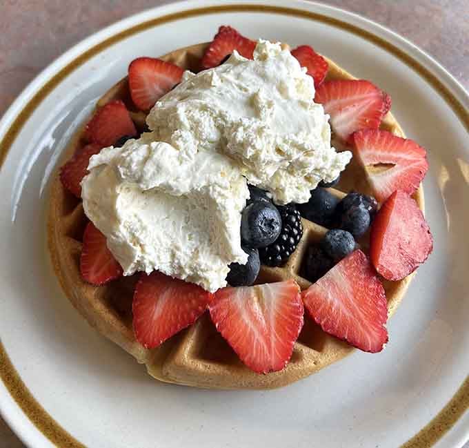 Fresh strawberries and blueberries crown this Belgian waffle like edible jewels on a golden, crispy throne of deliciousness.