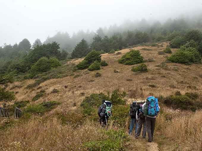 Backpackers brave the elements on trails where fog adds atmosphere and a touch of mystery.