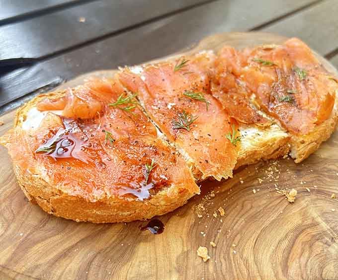 Smoked salmon on crusty bread with dill, proving this plane serves better food than any airline ever did.