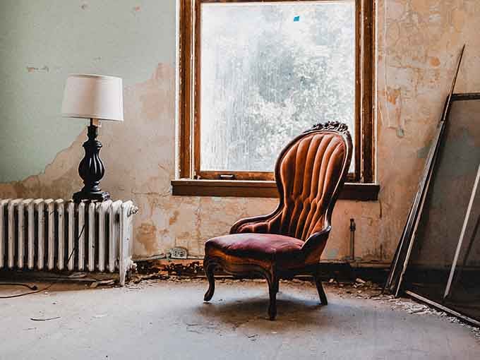A Victorian chair and vintage lamp create an oddly domestic scene, as if someone tried decorating during the apocalypse.