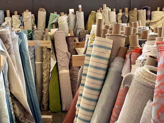 Fabric rolls stacked like a textile tower of Babel, each pattern telling its own decorative story.