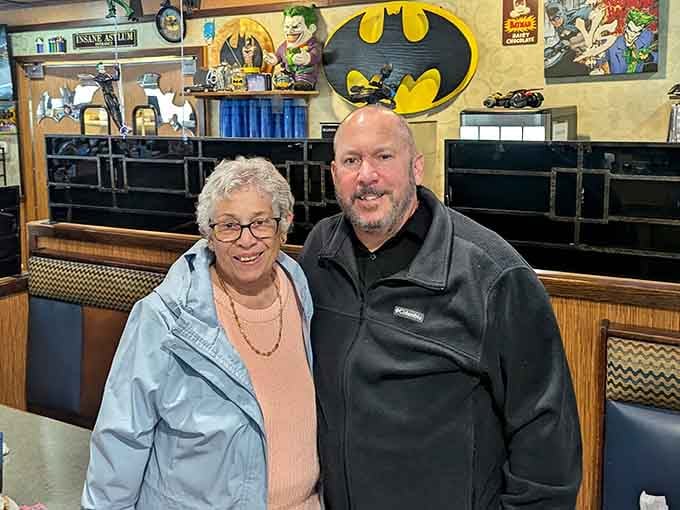 Happy diners pose beneath the iconic Batman logo, proof that good food and fun decor create memorable experiences.
