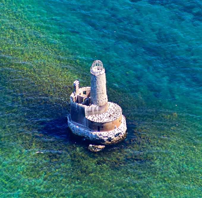 The aerial view shows just how isolated this lighthouse is, sitting on its limestone crib like a forgotten island.