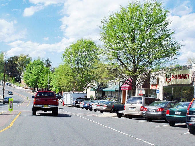 Spring trees frame the pharmacy and local shops where everyone still knows your name and your usual order.