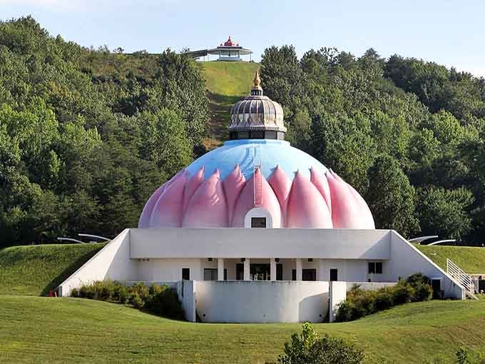 Pink dome shrine rises boldly from hillside, a striking architectural statement celebrating spiritual unity and peace.