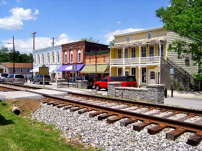 Railroad tracks slice through the scene like a timeline, connecting past and present while those cheerful storefronts promise a bright future.