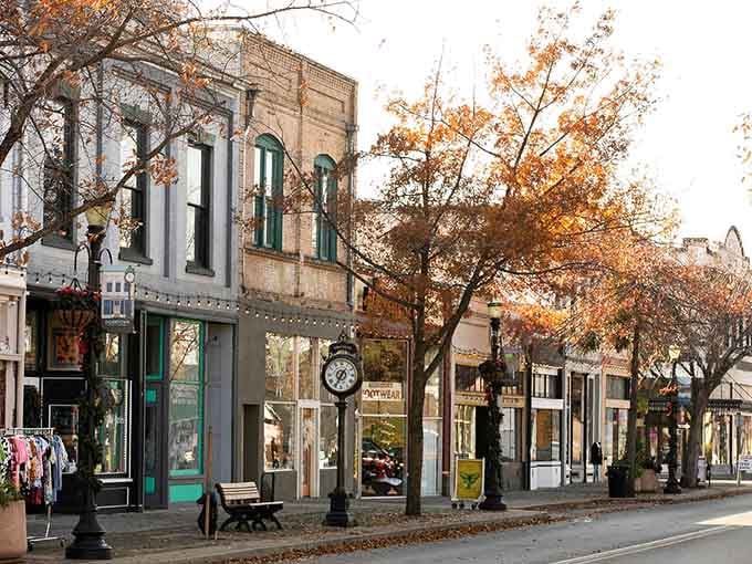 Autumn leaves frame historic storefronts where the clock tower still keeps time for an unhurried community.