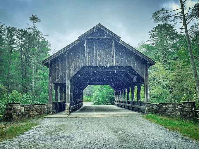 Rain falls on this weathered covered bridge, its dark wood and stone foundation standing strong against time and elements.