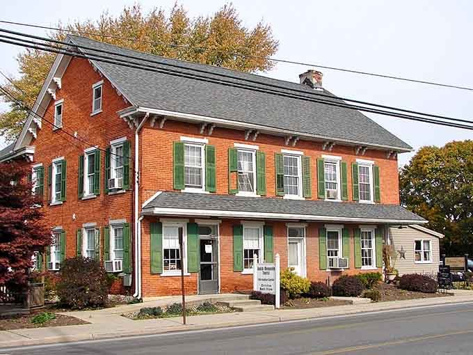 Green shutters pop against warm brick on this substantial corner building, showing how traditional architecture ages gracefully when properly maintained.