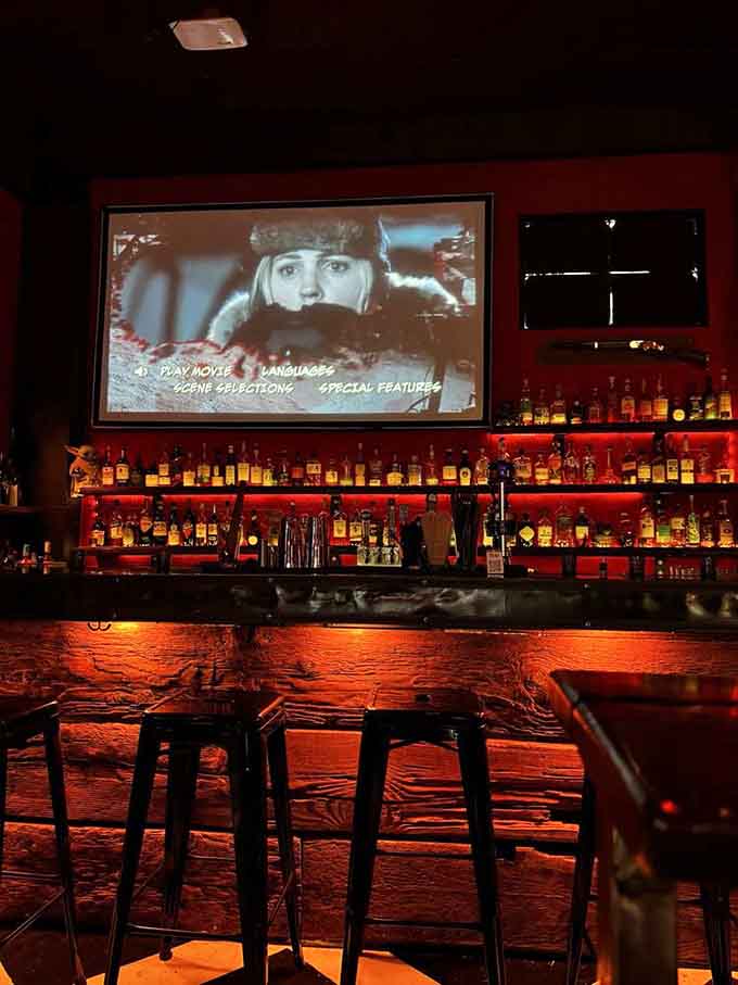 Red-lit shelves stacked with bottles and a horror film playing above the bar, this is the good life.