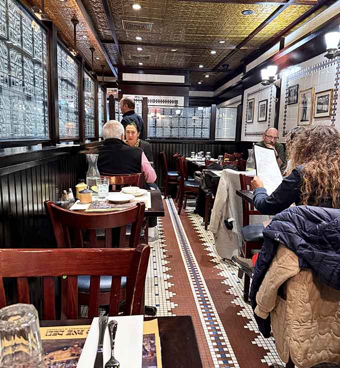 The dining room buzzes with that perfect New York energy where strangers become friends over impossibly large sandwiches.