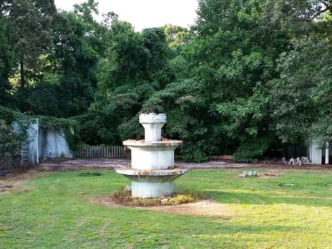 This weathered fountain sits silent in the overgrown grounds, waiting for water that may never flow.