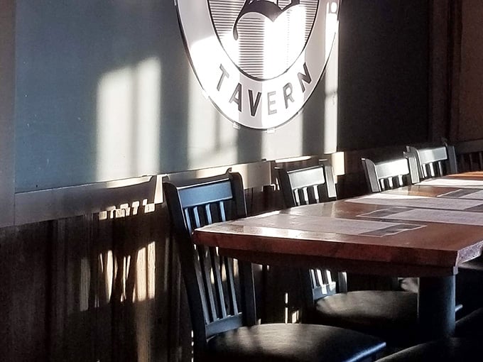 Long communal tables under that Tavern logo create the kind of gathering space where strangers become friends over good food.