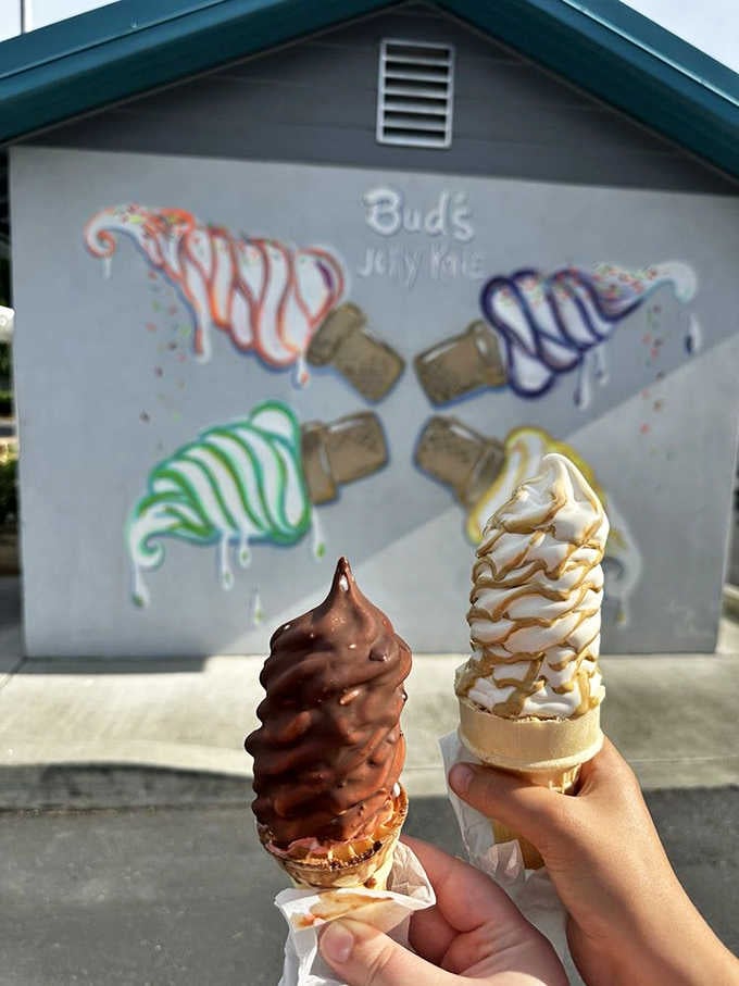 Two cones dipped in chocolate and caramel stand before their mural inspiration like edible works of art.