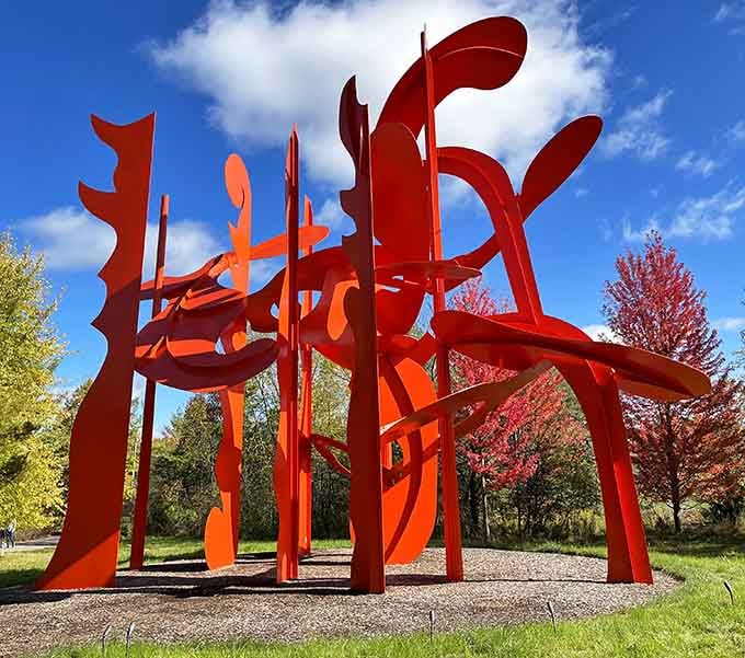 Bold red steel sculpture cuts through autumn colors, proving that contemporary art and nature make spectacular companions together.