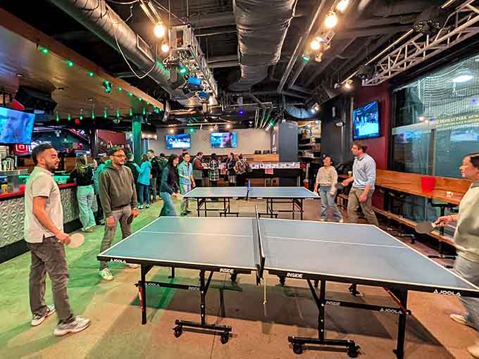 Kids in team jerseys gather around arcade games, proving that sports bars can absolutely be family-friendly destinations too.