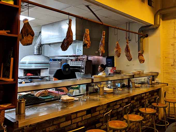 Country hams hanging overhead like delicious art installations, because why shouldn't your kitchen double as a gallery?