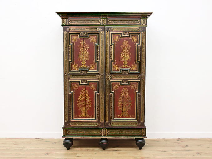 A boldly painted armoire covered in gold flourishes, because sometimes a wardrobe deserves to be the star.