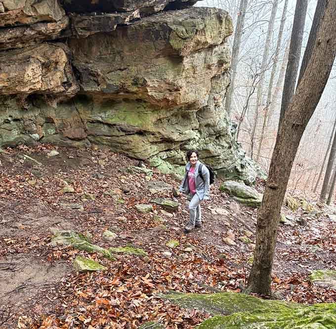 Moss-covered boulders and towering sandstone cliffs dwarf a hiker exploring this geological wonderland frozen in time.