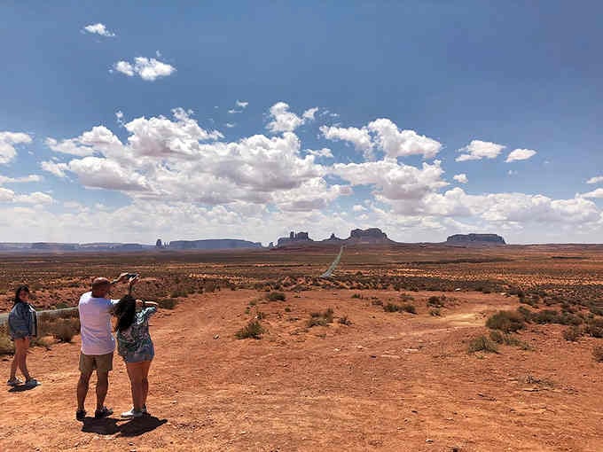 Three people, infinite landscape, and the universal realization that some views demand to be shared immediately.