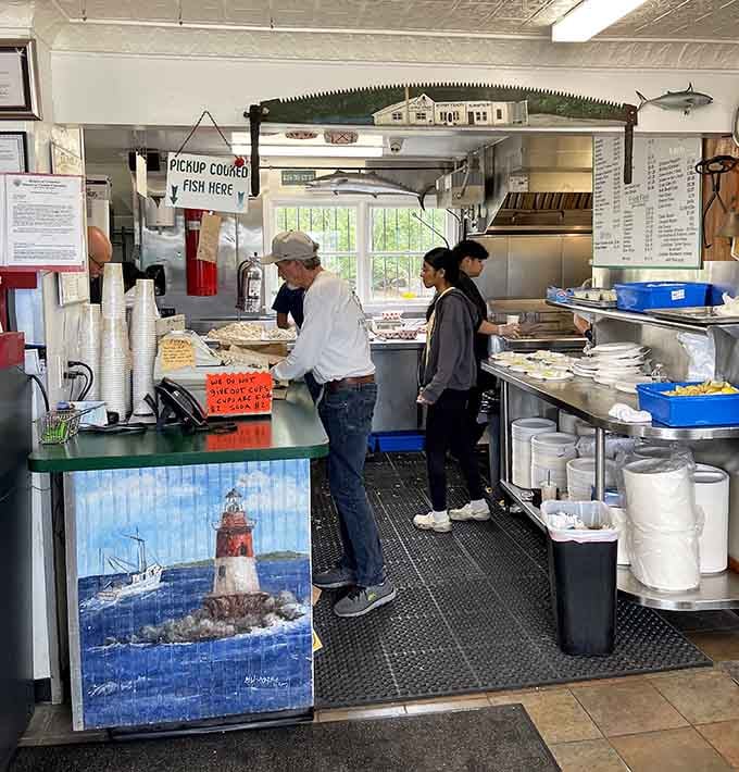 The "Pickup Cooked Fish Here" sign and that lighthouse artwork tell you everything about this spot's straightforward, nautical-themed approach to service.