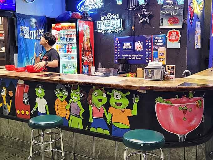 Bar seating decorated with cheerful alien friends who clearly know how to throw an intergalactic pizza party.