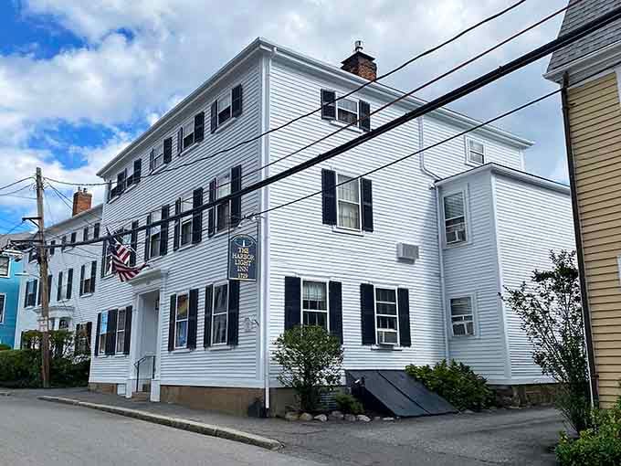 The Harbor Light Inn stands crisp and welcoming, its white facade practically glowing with New England hospitality.