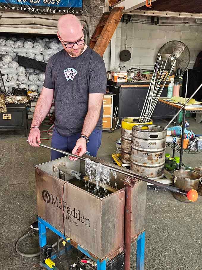 A visitor carefully shapes molten glass, experiencing the thrilling intersection of art, science, and controlled chaos firsthand.