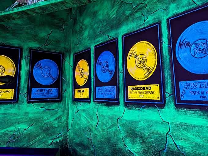 Gold records glow like treasures in a cave, celebrating legends from Nirvana to Radiohead in fluorescent tribute.