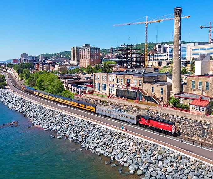 An aerial view revealing the train hugging Duluth's shoreline like it's showing off Minnesota's best-kept scenic secret.