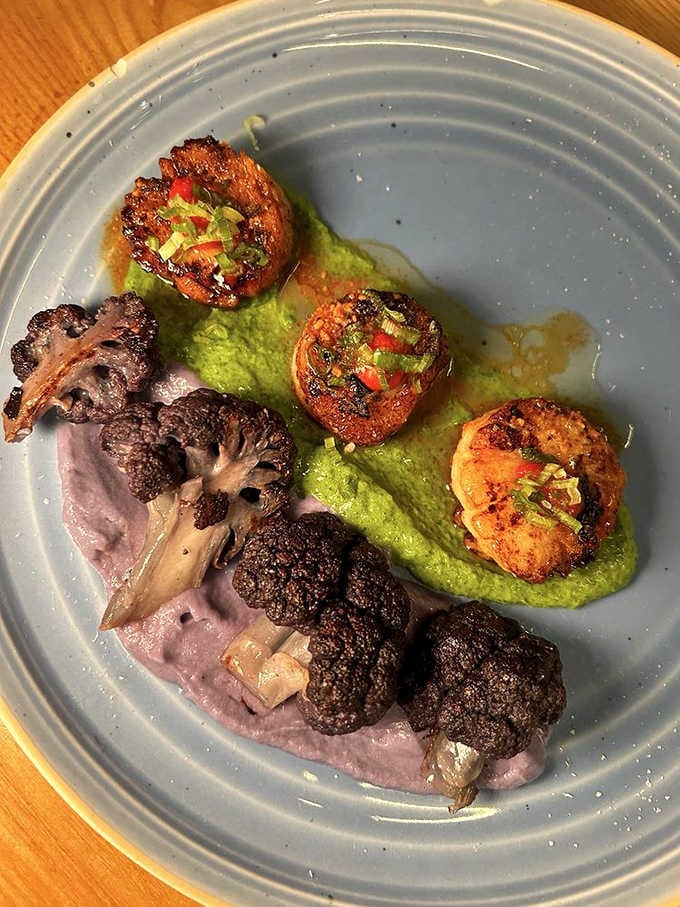 Seared scallops nestled on vibrant purple cauliflower puree prove that plating can be both artistic and absolutely mouthwatering.