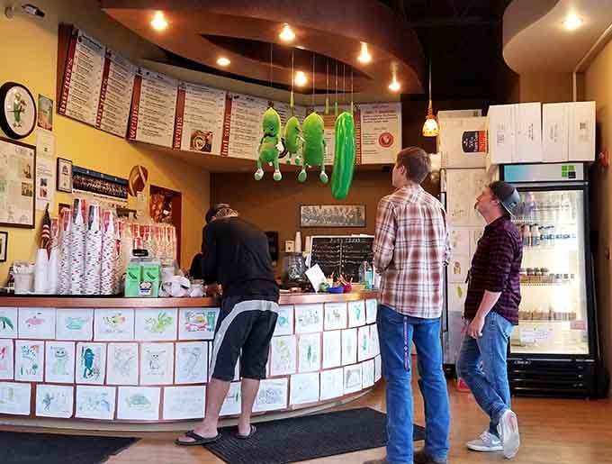 The ordering counter where pickle dreams become reality, decorated with customer art that celebrates fermented cucumber joy.