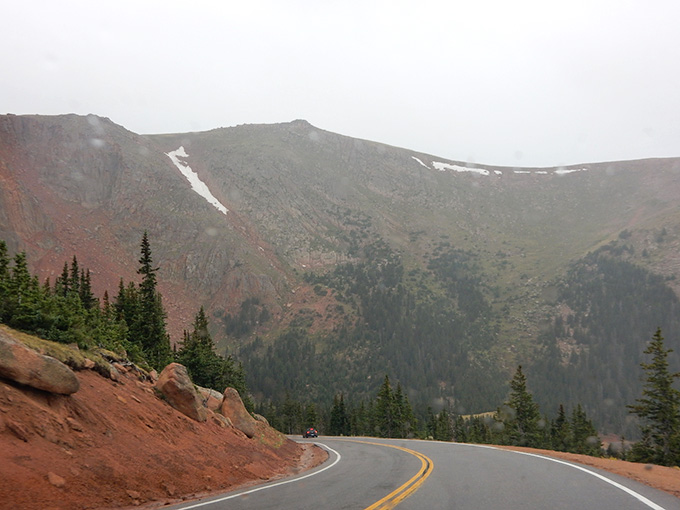 Storm clouds gather above while the road continues its relentless climb toward the sky itself.