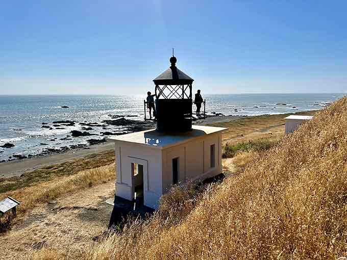 The lighthouse stands proud against golden skies, still commanding respect despite its weathered, abandoned state.