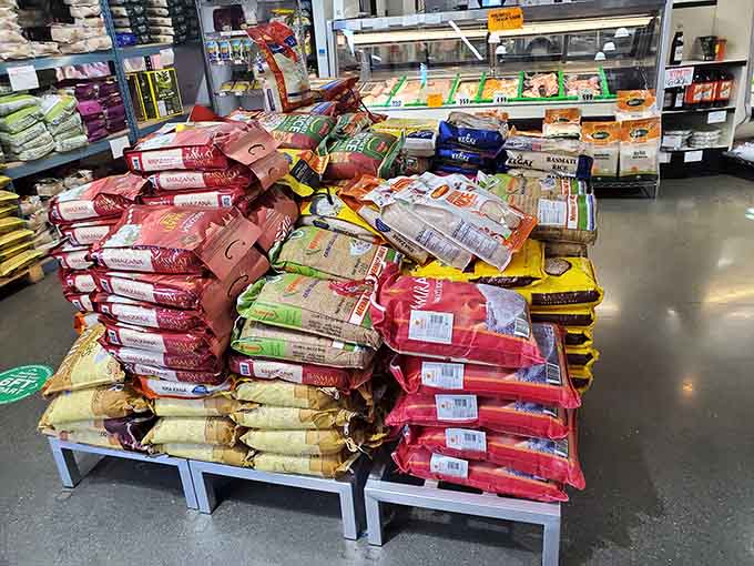 Rice bags stacked higher than your grocery list ambitions, representing every grain tradition from jasmine to basmati bliss.