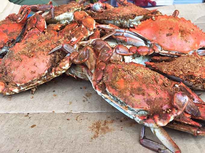 Steamed crabs wearing their traditional red seasoning like they're dressed up for a summer celebration you're invited to join.