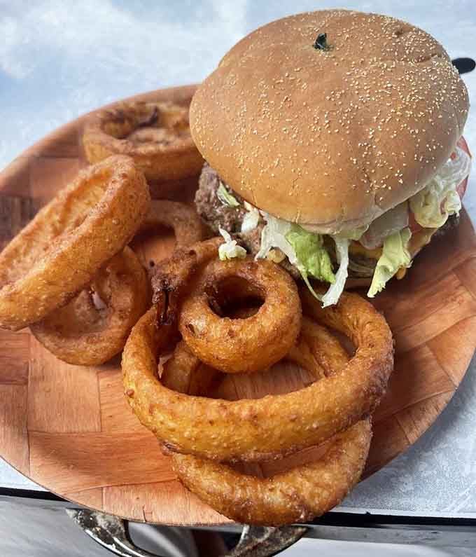 Those onion rings stacked around the burger look like edible architecture, and you're about to become a very happy demolition crew.