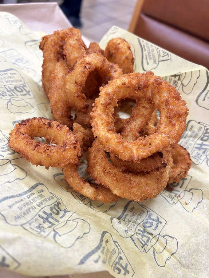 Golden onion rings stacked high, crispy and seasoned, proving sides here deserve equal billing with mains.