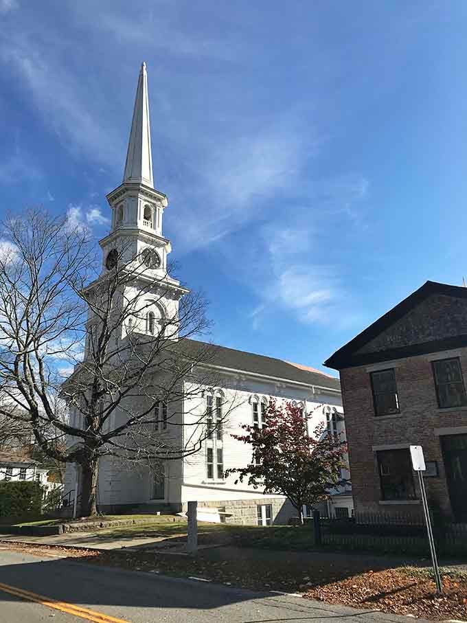 White steeple reaching skyward against autumn leaves, the quintessential New England church that's graced a thousand postcards deservedly.