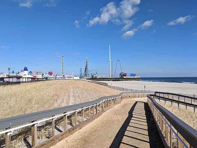Wooden boardwalk stretches toward distant amusements while pristine sand waits patiently for summer crowds to return again.