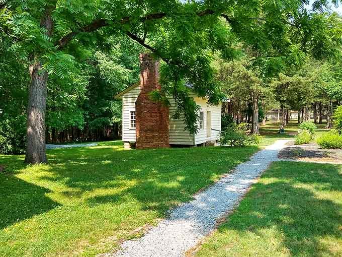 A historic cottage sits nestled in green lawn, looking like it wandered out of a colonial-era postcard collection.