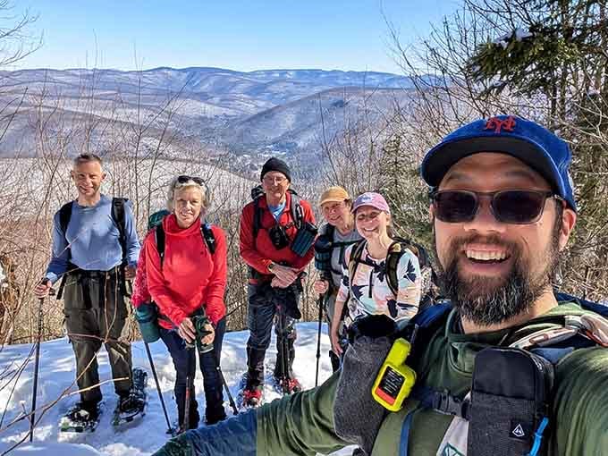Winter hiking crew grinning wide despite the cold, proving that frozen noses and mountain views make the best memories together.